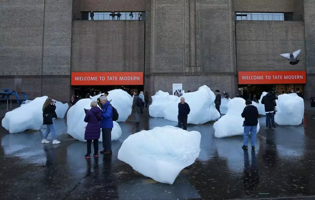 Ndị ọbịa na-emekọrịta ihe na ngọngọ nke ice na-agbaze site na ihe ngosi akpọrọ Ice Watch nke onye omenkà Icelandic-Danish mere Olafur Eliasson na onye isi Greenlandic geologist Minik Rosing na mpụga Tate Modern na etiti London na Disemba 11, 2018. Foto: Daniel Leal-Olivas/AFP/Getty Onyonyo.