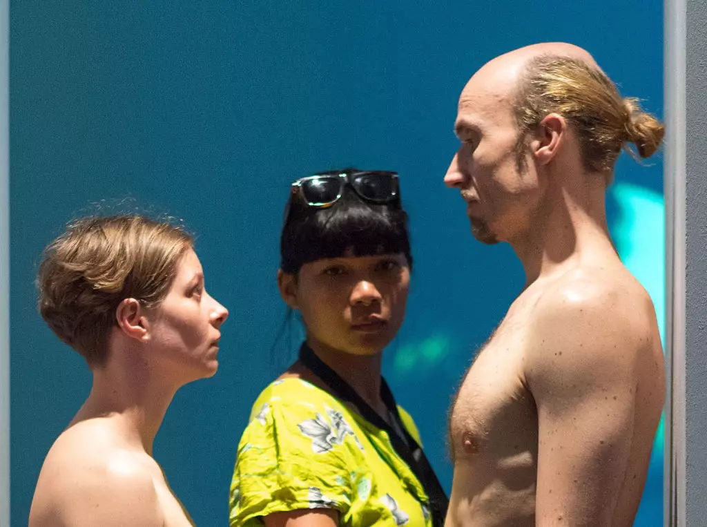 Une femme entre dans la reconstitution de la performance Imponderabilia (1997/2017) en marchant entre un homme nu et une femme nue à l'exposition d'art