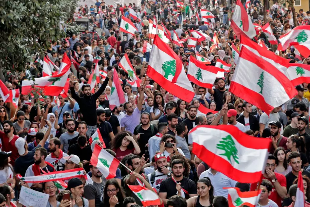 Lübnanlı protestocular, 21 Ekim 2019'da Beyrut şehir merkezinde, daha iyi yaşam koşulları ve on yıllardır gücü ve nüfuzu tekelinde tutan bir dizi politikacının devrilmesini talep etmek için gösteriler sırasında ulusal bayraklar sallıyorlar. Fotoğraf: Getty Images aracılığıyla Anwar Amro/AFP.